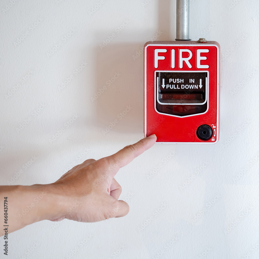 Emergency fire warning system pull station. Hand pointing at red fire ...