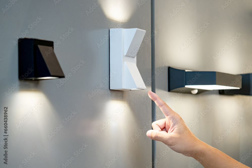 Designer hand pointing at sample of exterior LED wall lamp in home ...