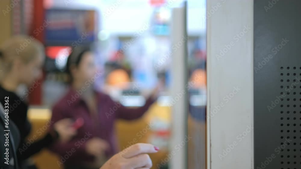 Girl using touch terminal makes a quick order through the self-service ...