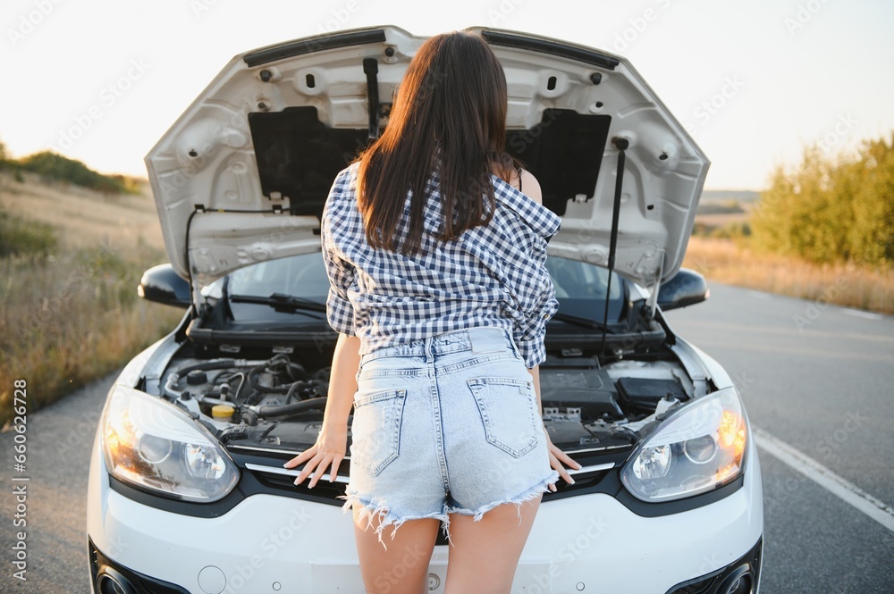 sexy girl stand by the broken car and don't know what to do. Rear view. Photos | Adobe Stock