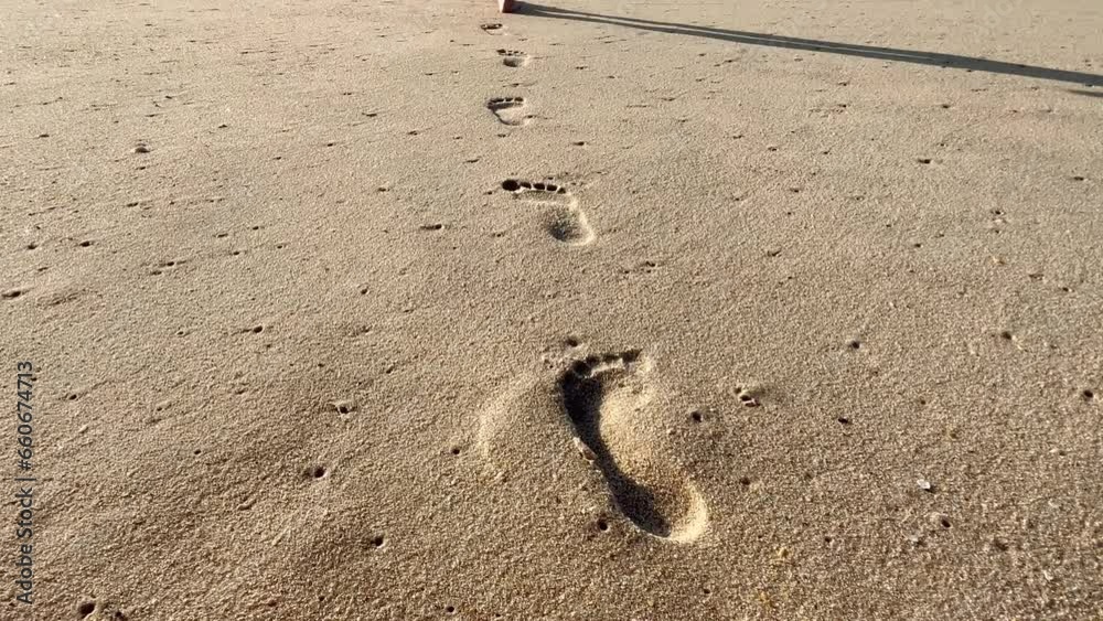 Footprints in the sand on the beach. The camera follows footprints of ...