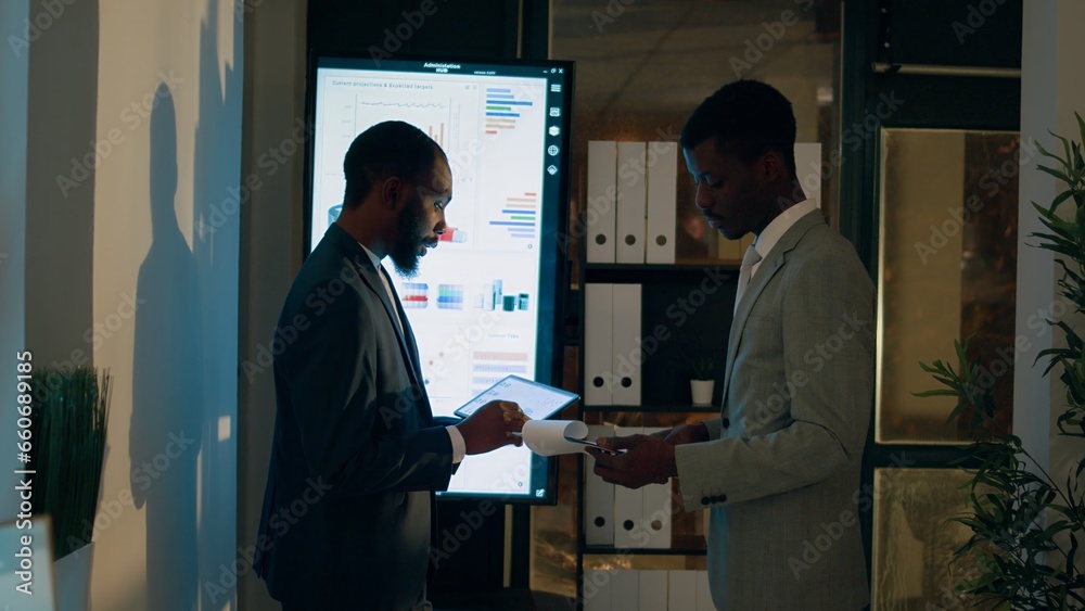 Supervisor debriefing assistant in front of digital screen, showing him ...