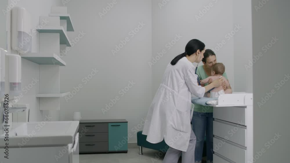 Mother Holds Her Cute Baby In Diaper And Puts Him On Changing Table
