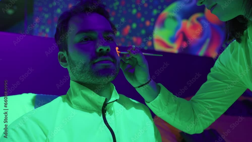Young peoples are having fun in a neon amusement park, the girl draws ...