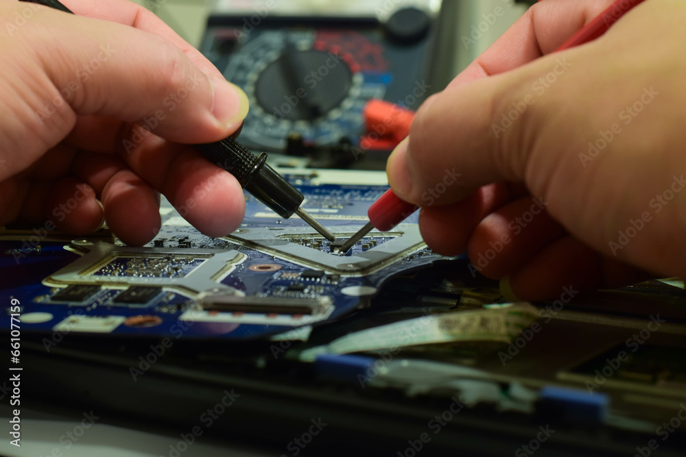 computer technician A laptop motherboard repairman is using an IC meter ...