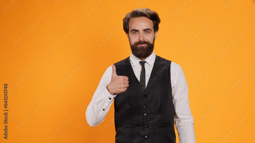 Stylish butler shows thumbs up gesture in studio, indicating positive ...
