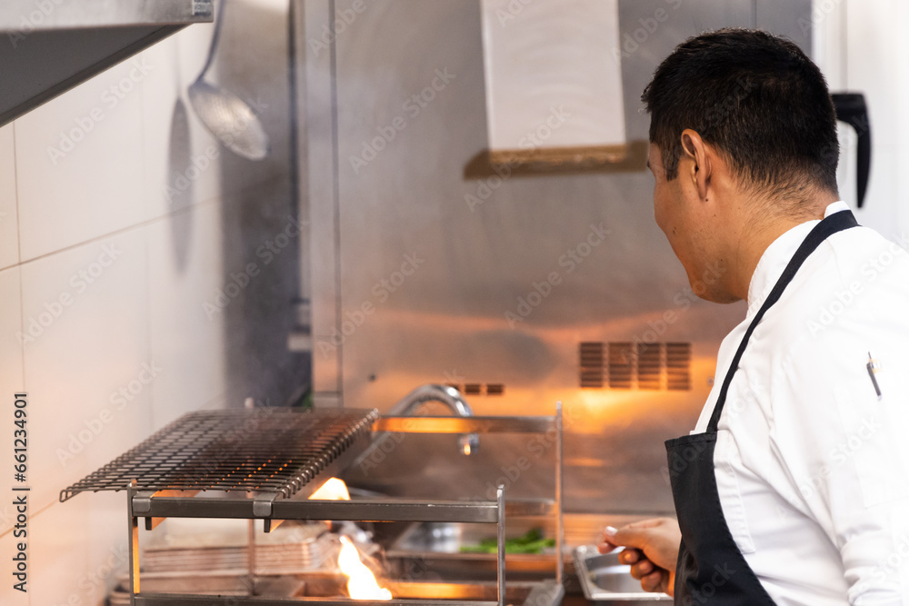 Side photo of a Latin chef cooking with fire on the kitchen grill Stock ...