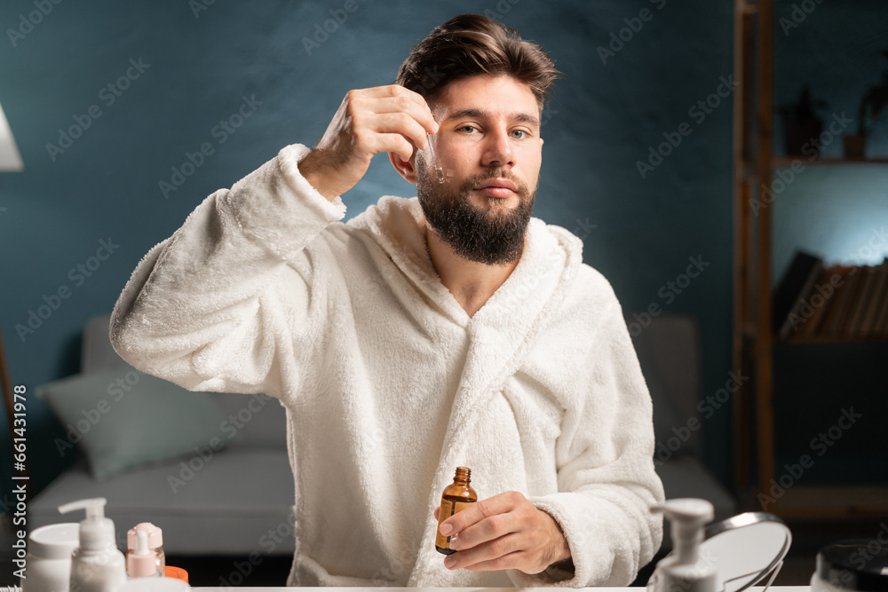 beautician applying gel serum on bearded man face using glass pipette ...