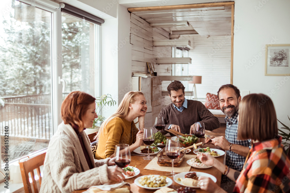 Diverse group of friends eating lunch together at home during winter ...