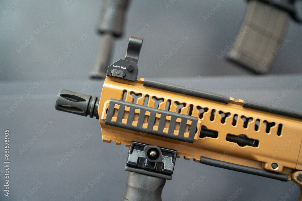 Sand-coloured camouflaged assault rifle with short barrel and metal ...