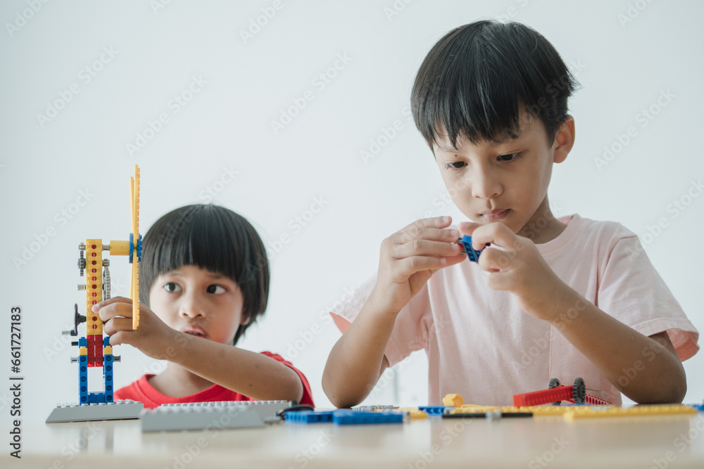 Two cute Asian Thailand boys, ages 3-6, are standing and building mini ...