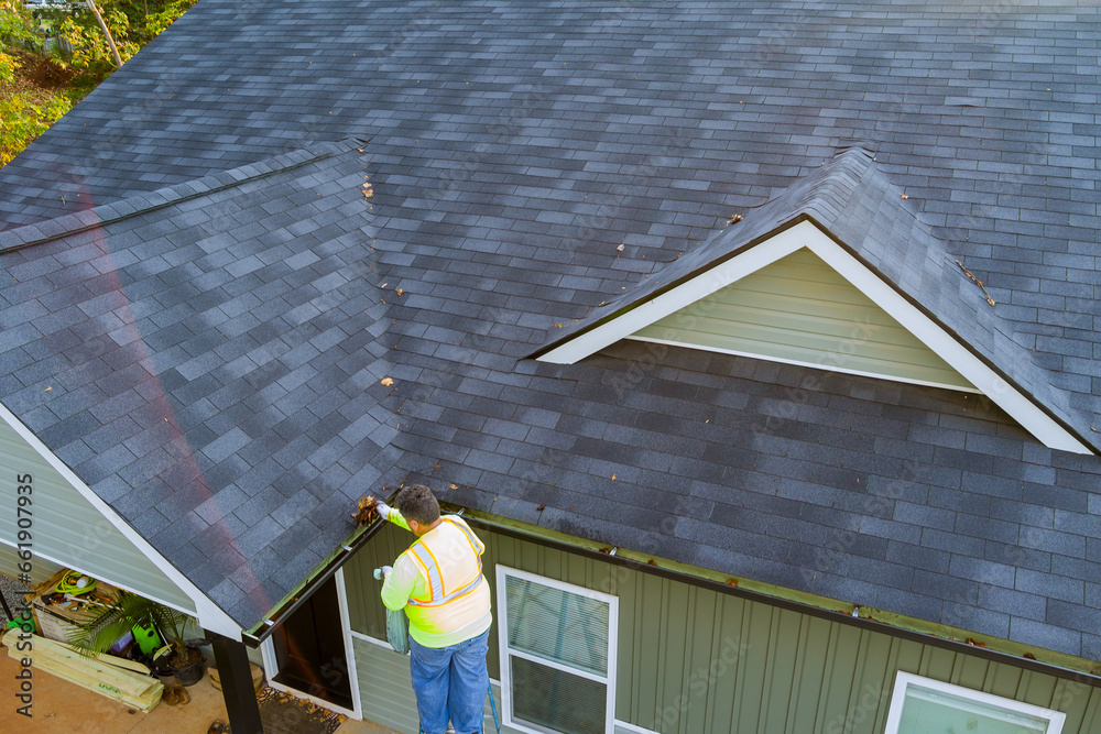 Worker cleans clogged roof gutter drain from dirt debris, as well as ...