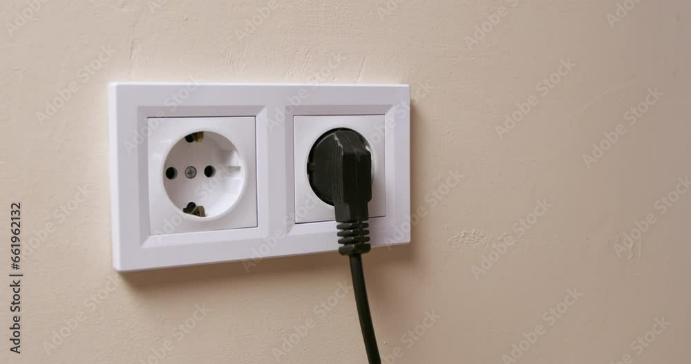 Close-up, a man inserts a wire plug into a socket, connecting the ...
