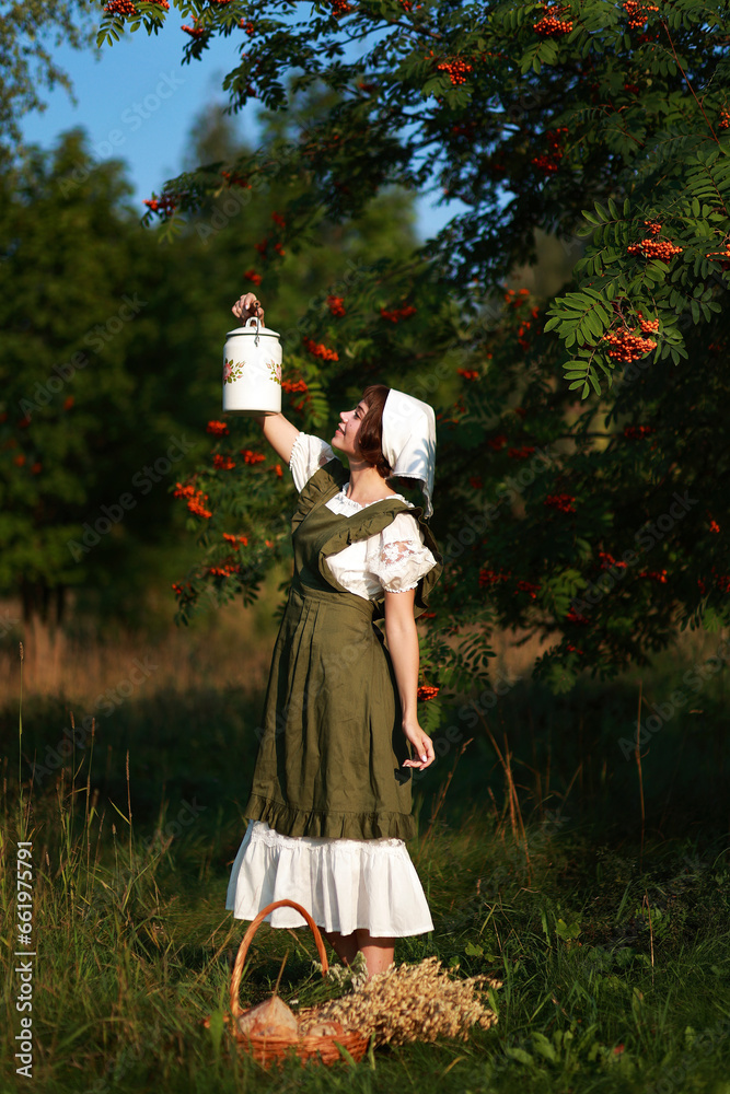 Young peasant woman in white village dress and green apron with basket ...