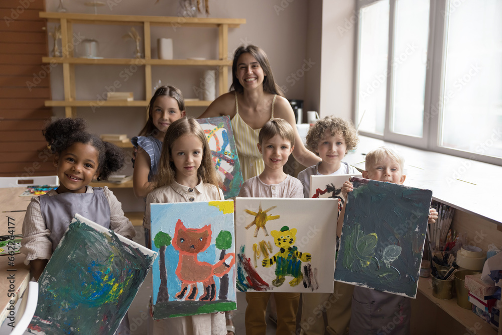 Foto de Cute multiethnic children showing their paintings to camera ...