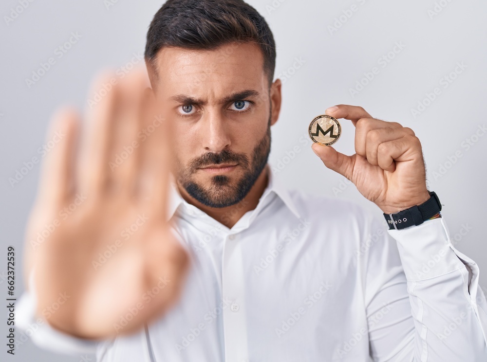 Handsome hispanic man holding monero cryptocurrency coin with open hand ...