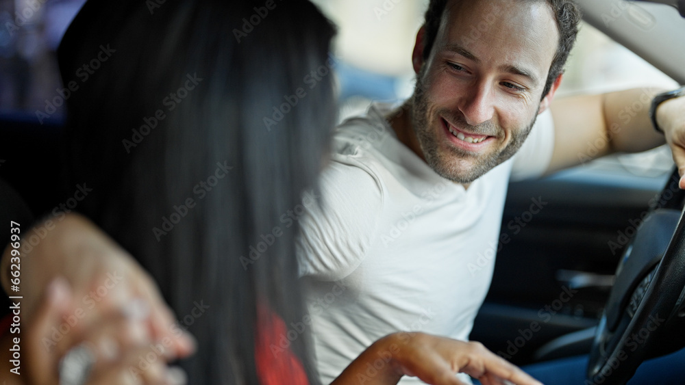 Beautiful couple hugging each other sitting on car smiling at street ...