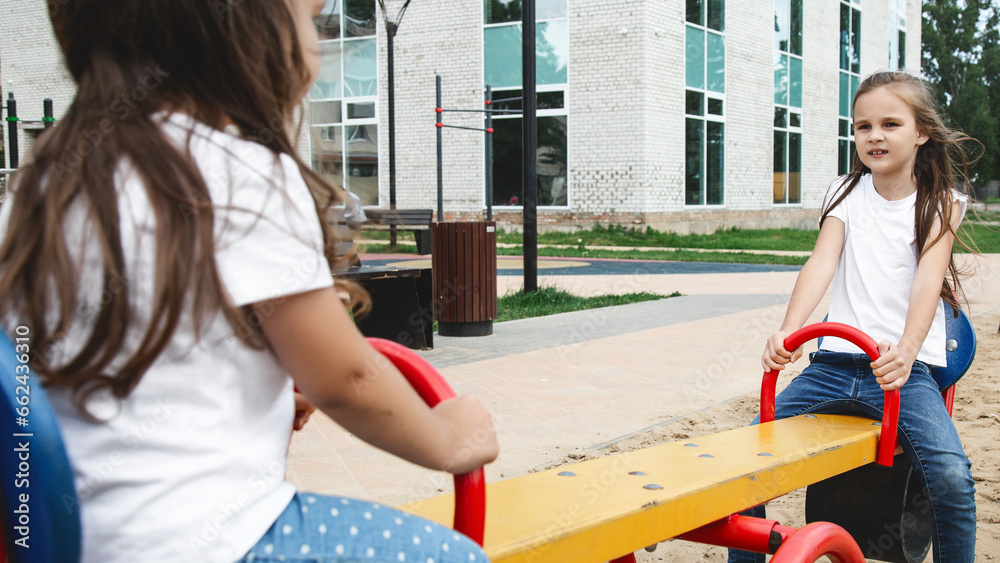 Kids playing at the see-saw in the playground. Children have fun in ...