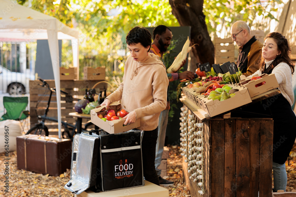 Food delivery worker putting fresh natural produce box in bag and ...