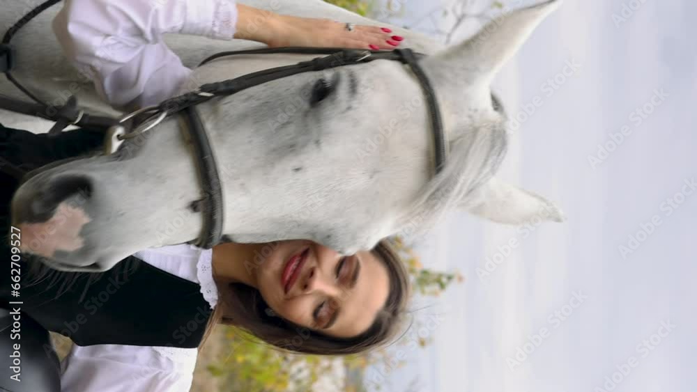 portrait of beautiful woman riding horse in orchard,touches horse ...