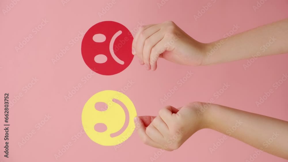 Vertical video of female hands holding happy and angry face paper ...