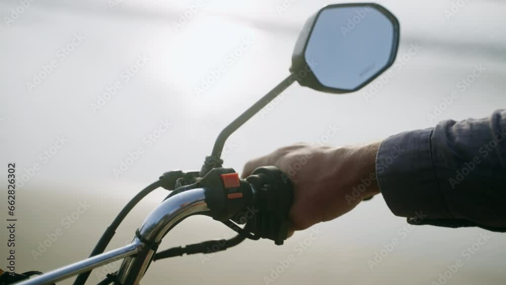 Biker puts hand on motorcycle handlebar on seaside. Person holds ...