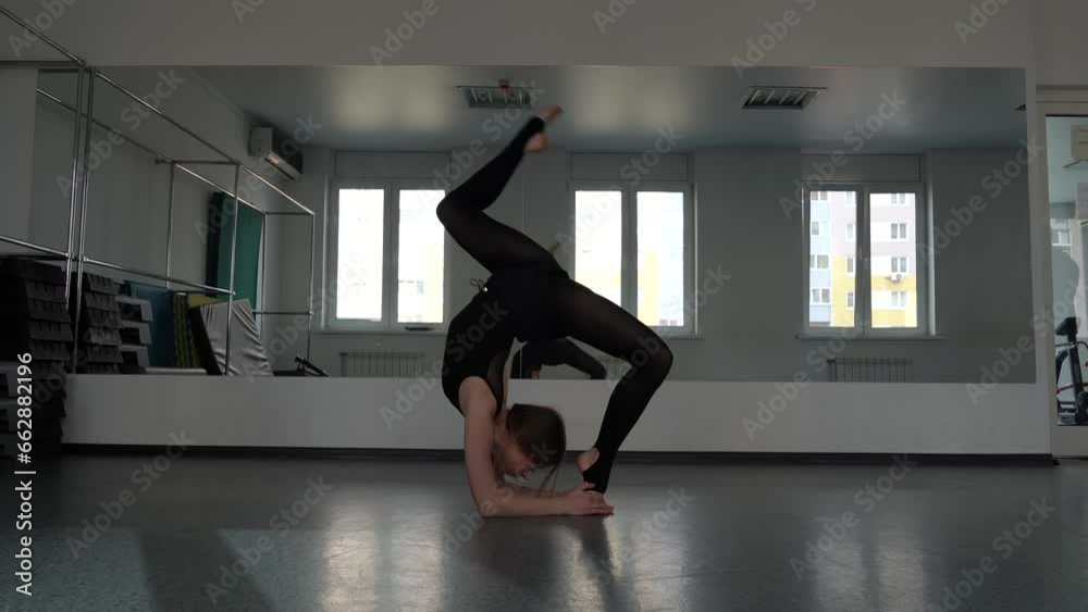 girl gymnast pulls leg to head arching in the back, stretching in ...