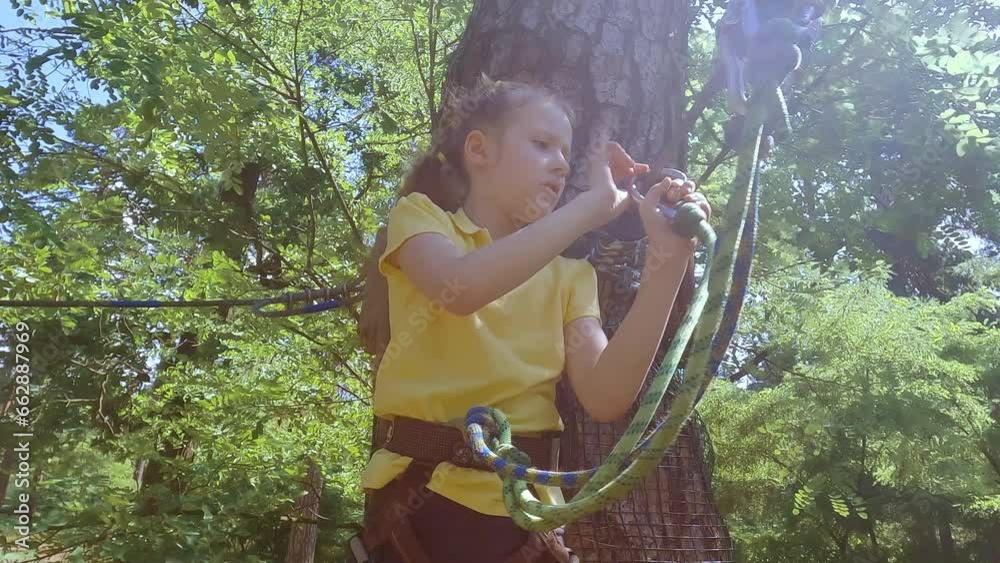 A child in a forest adventure park made of ropes. The girl is climbing ...