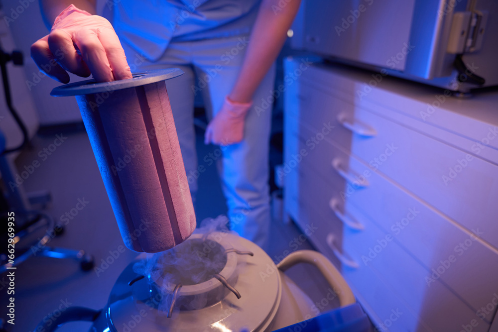 Lab worker using cryogenic container for preservation of biological ...