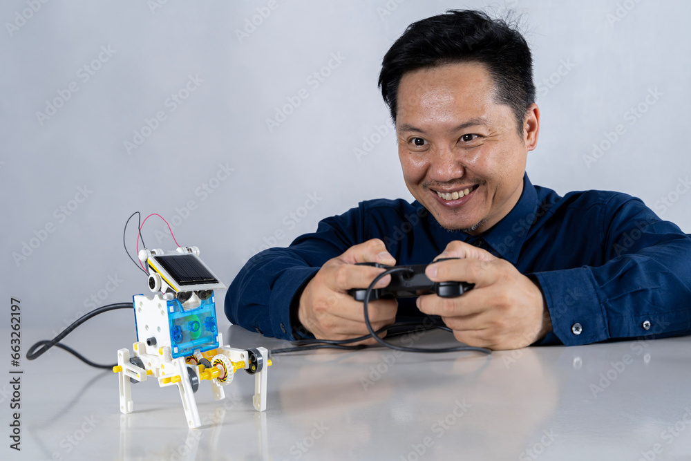 Asian man is building a robot project in his home. Robots control ...