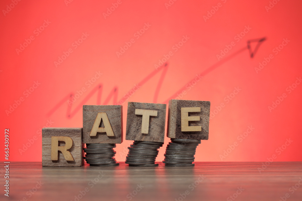 Wooden cube with the word RATE on the stacked coins. A graph pointing ...