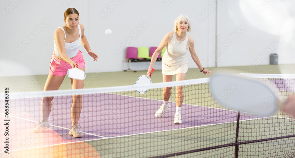 Expressive energetic girl playing doubles pickleball match in team with ...
