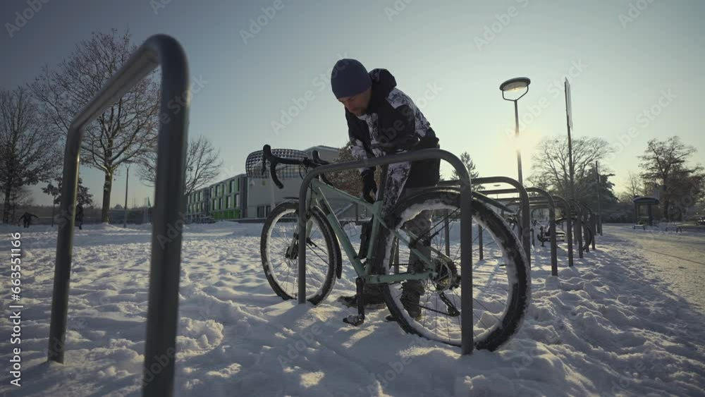 Cyclist attaches bicycle lock to street parking in Germany in winter ...
