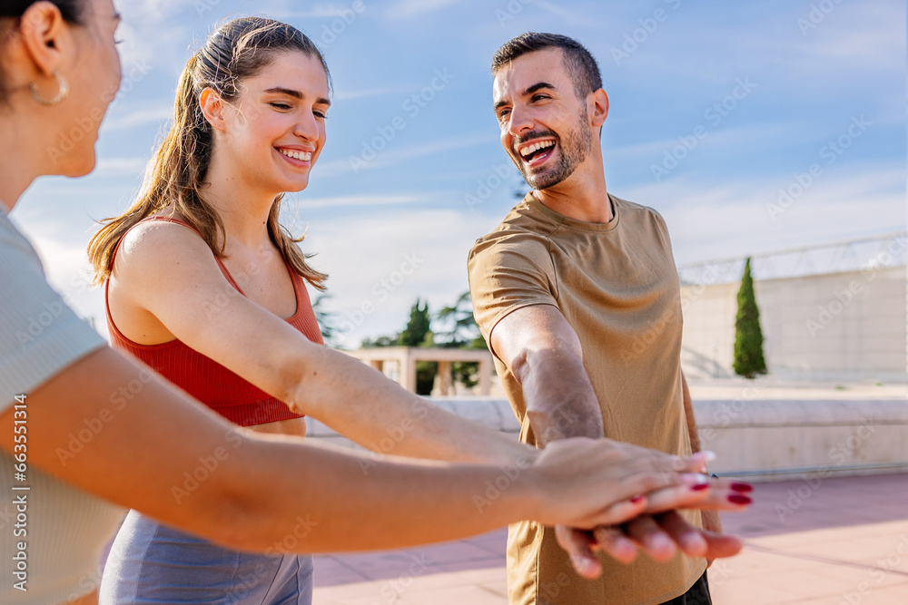 Young group of sportive friends stacking hands before workout routine ...
