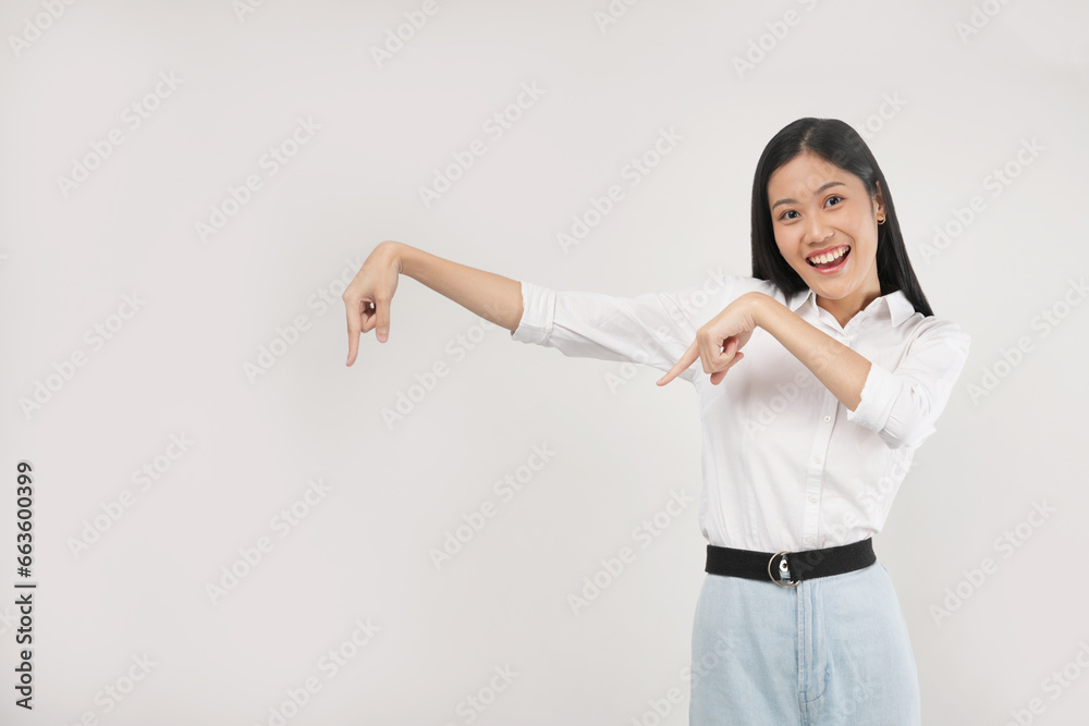 Portrait of a young Asian woman, pointing down and looking with a happy ...