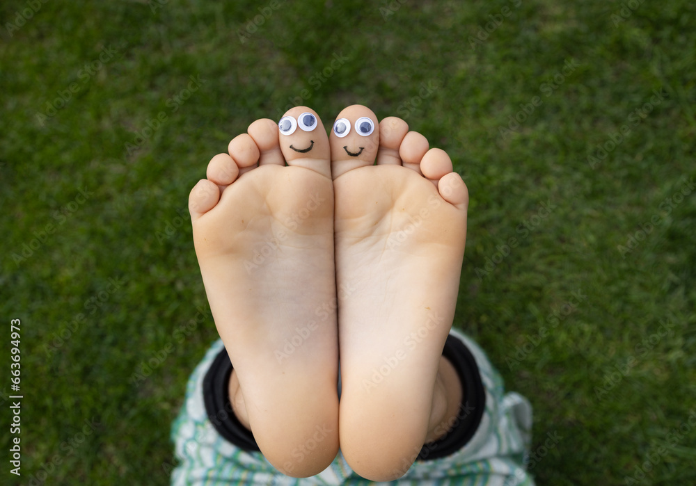 Children's bare feet with painted faces on the big toes. cheerful ...