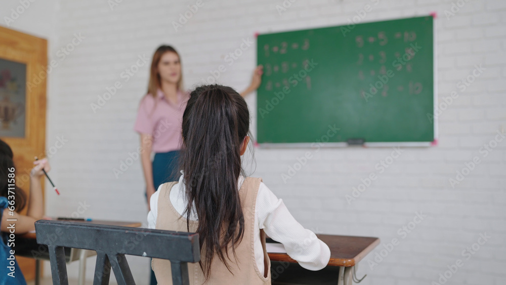 Kindergarten students listen to the female teacher in the classroom ...