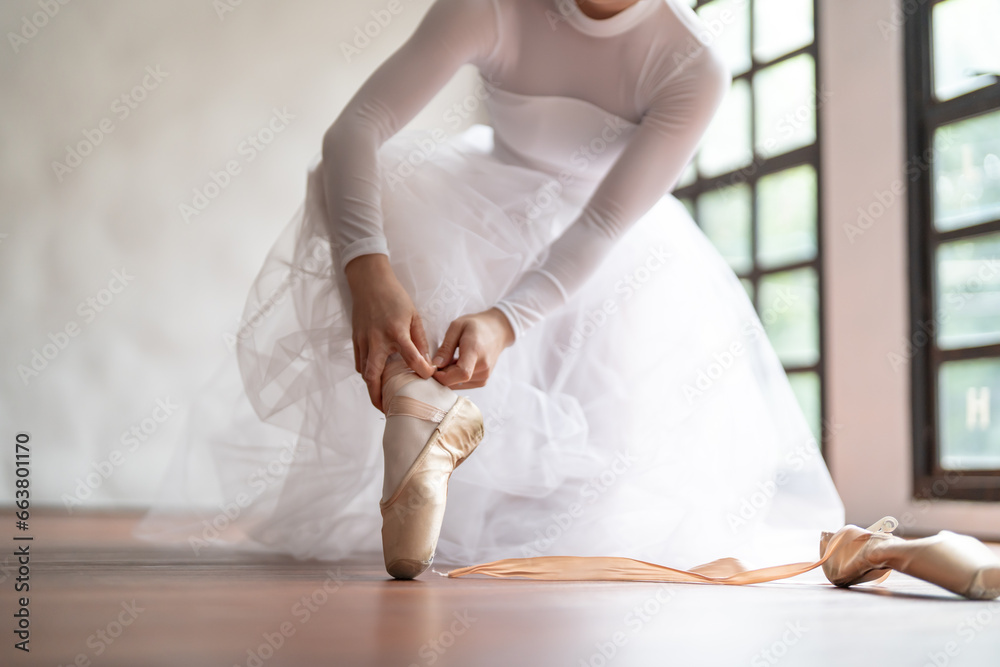 Ballerina in ballet shoes. Asian girl tying ribbons of toe shoes ...
