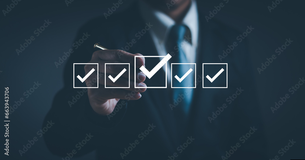 Businessman uses a pen to tick checkbox on business performance ...
