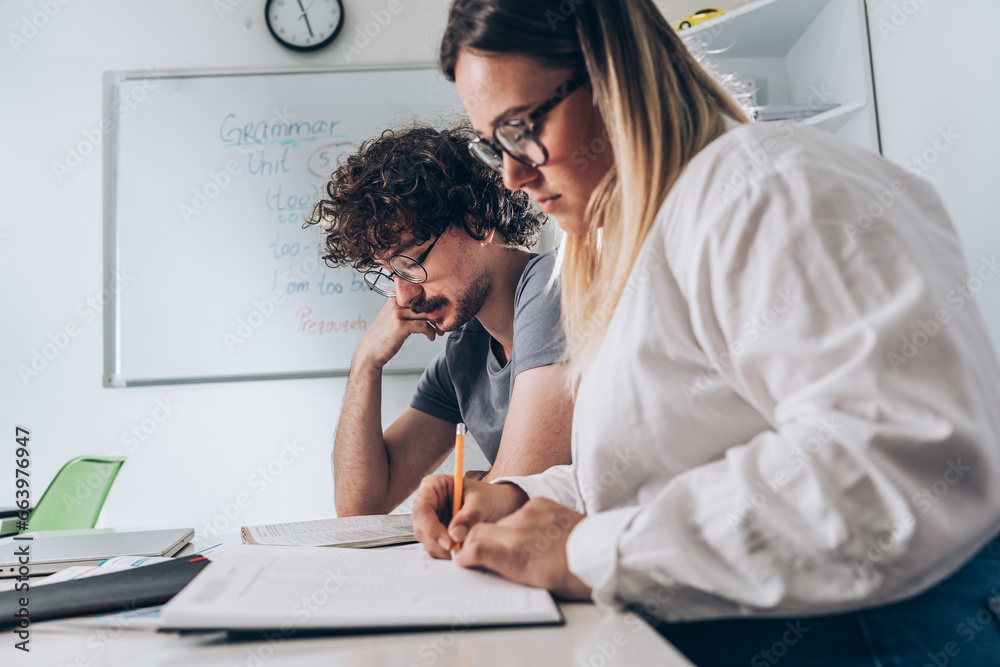 Two language learning students are focused on taking a test in their ...