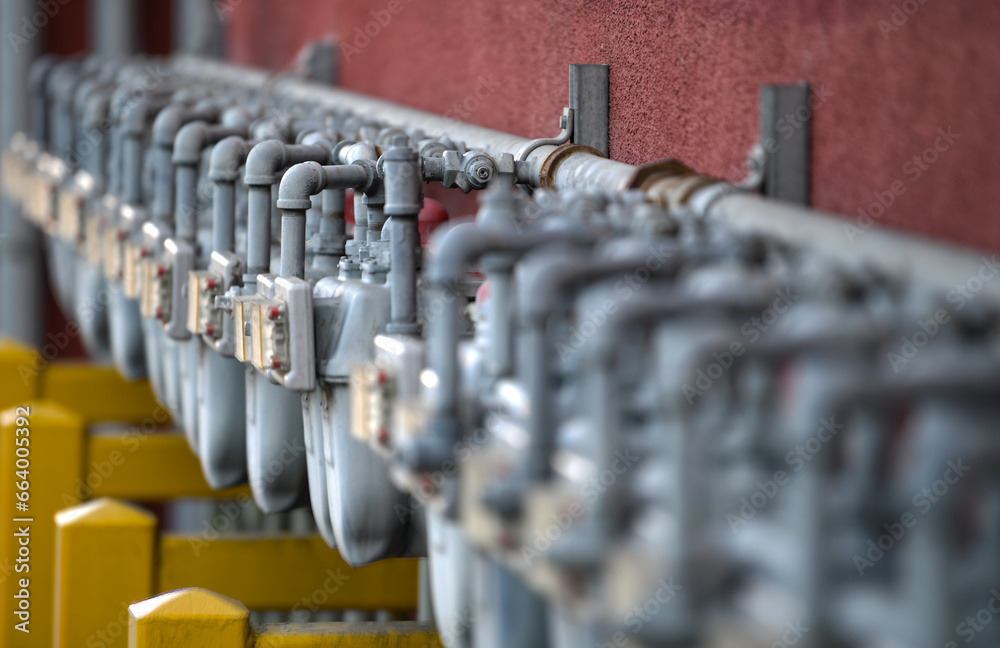 Bank of electric meters on a red stucco building protected by a series ...