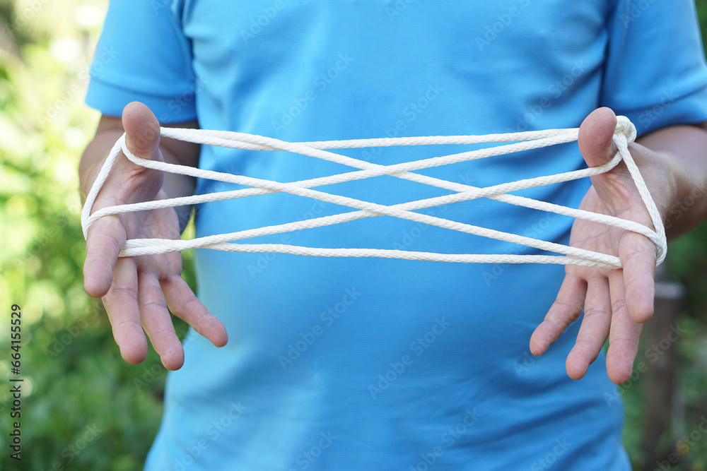 Closeup man hands is playing rope which called cats cradle game ...