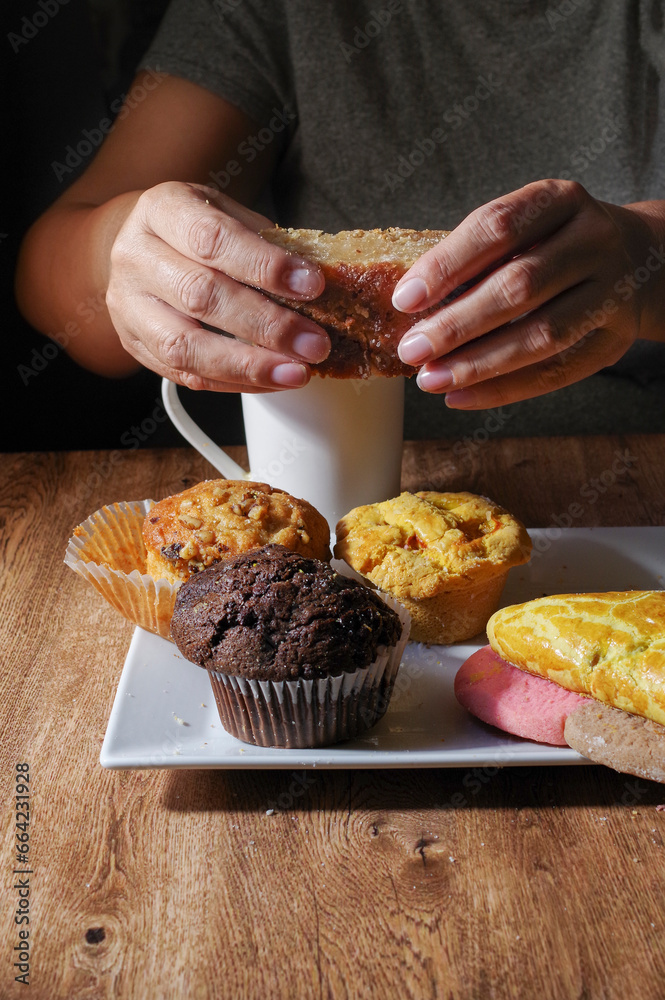 Woman's hand taking a piece of Mexican sweet bread from a white plate ...