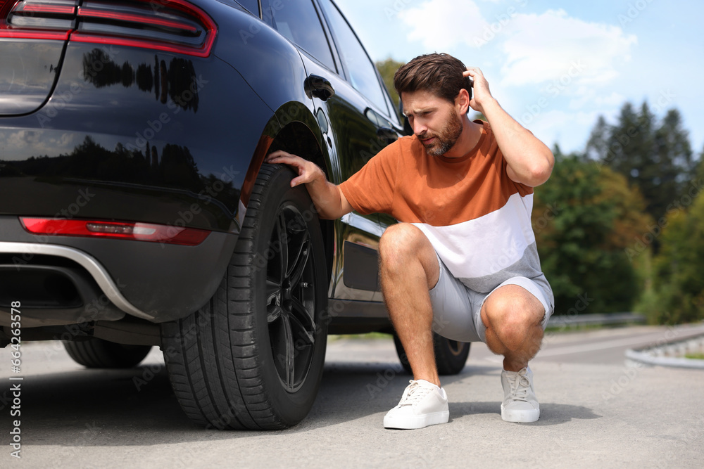 Tire puncture. Man checking wheel of car on roadside outdoors Stock ...
