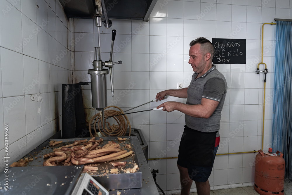 Cocinero friendo masa con dos palos de Churrero para hacer los churros ...