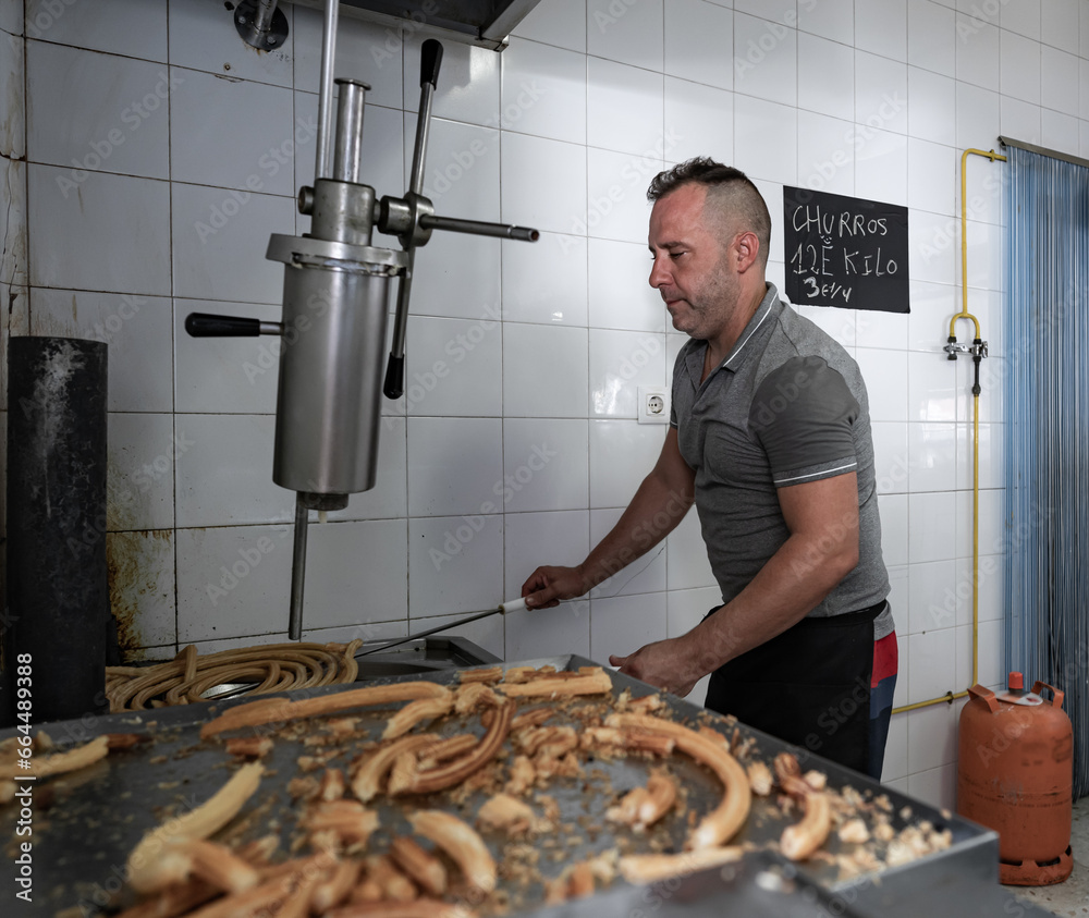 Cocinero friendo masa con dos palos de Churrero para hacer los churros ...
