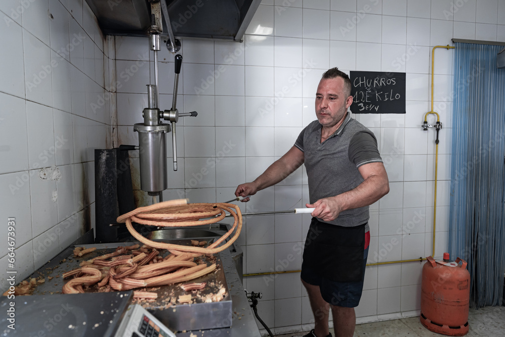 Cocinero sacando masa frita con los palos de churrero para hacer los ...