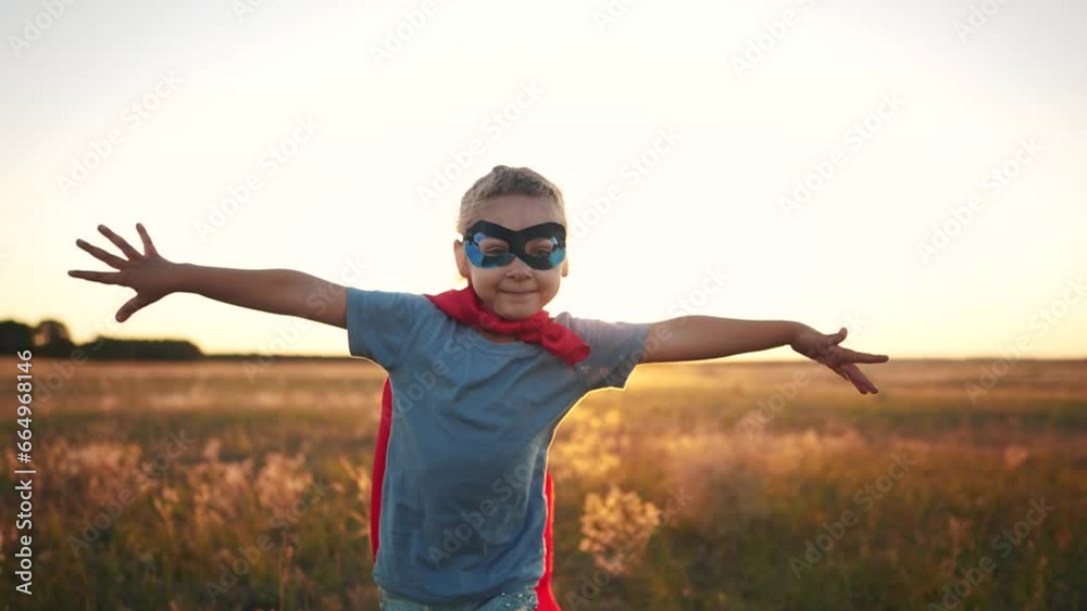 superhero girl runs across the field. happy family kid concept. a girl ...
