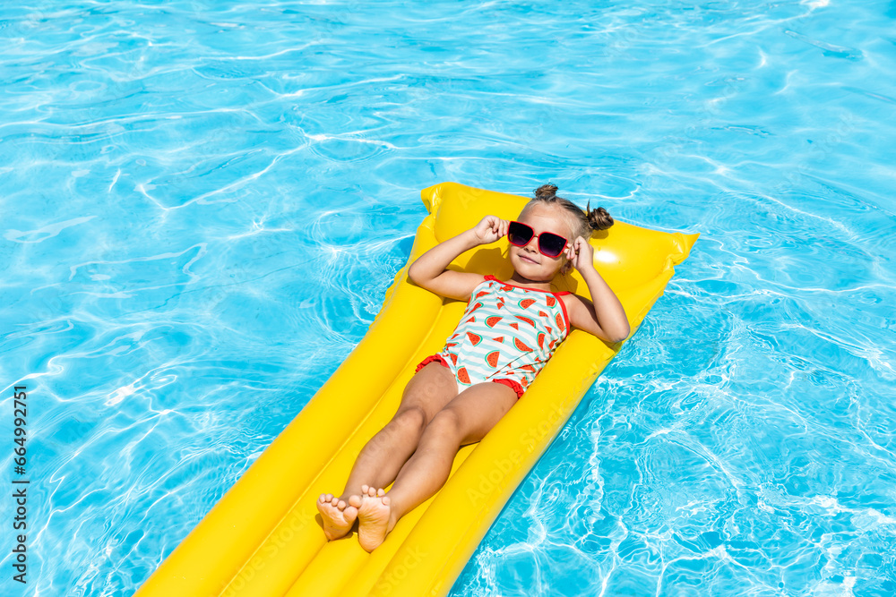 Cute little girl lying on inflatable mattress in swimming pool with ...