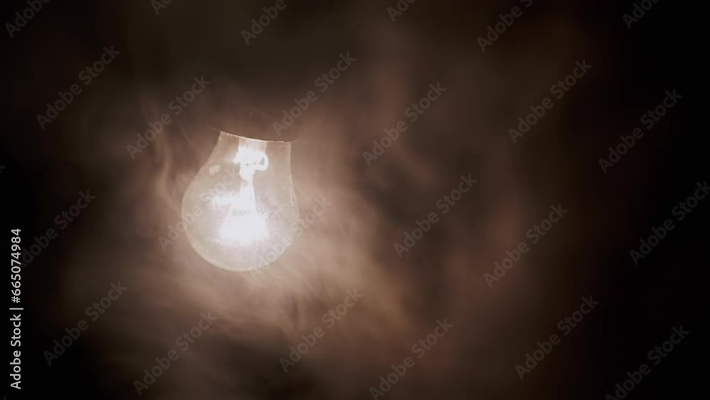 One Hanging, Glowing Light Bulb in Thick Smoke on a Black Background ...